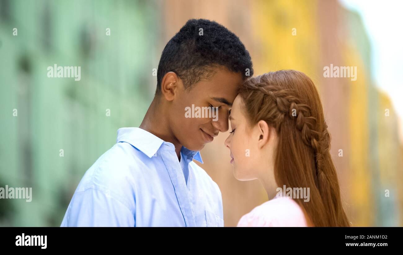 Multiethnic teen couple touching foreheads looking into eyes with love ...
