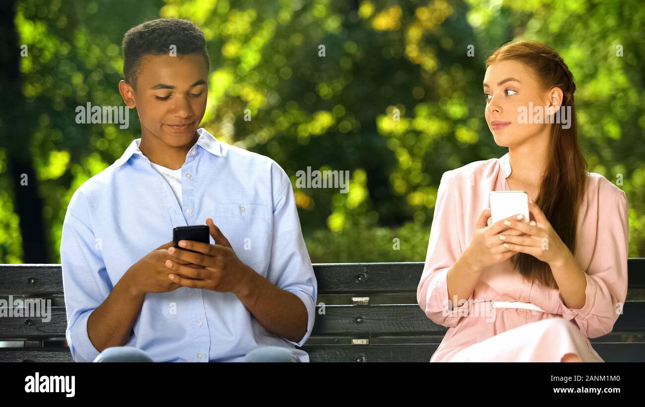 Beautiful red-haired lady ignoring man, sitting on bench in park ...