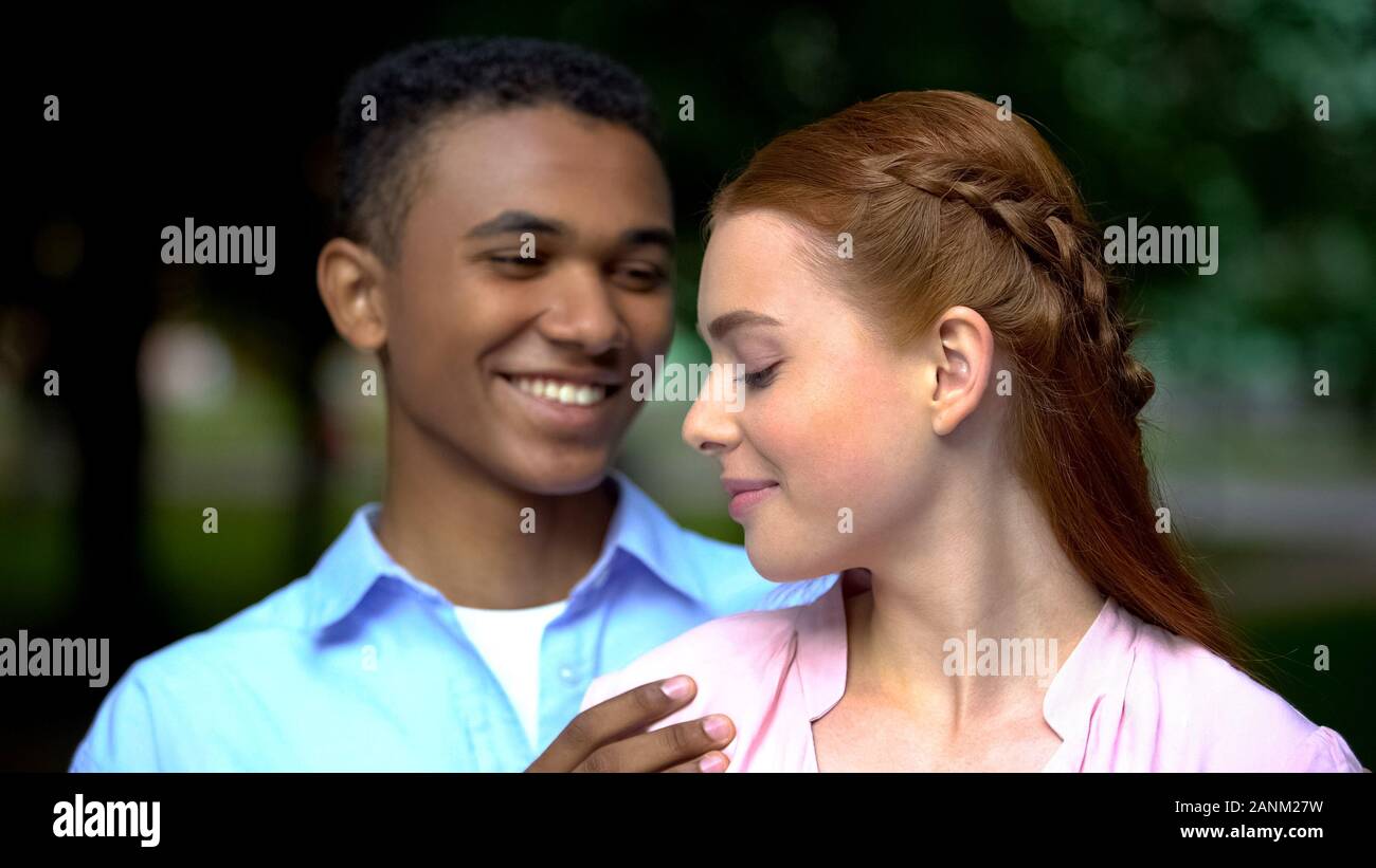 Beautiful mixed-race couple hugging looking at each other, tenderness ...