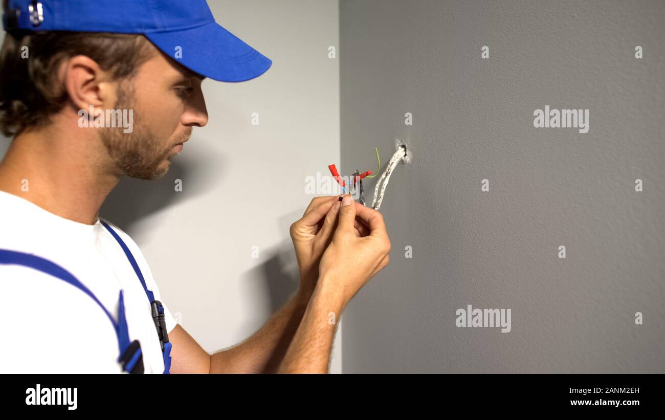 Repairman checking contacts by connecting two electrical wires ...