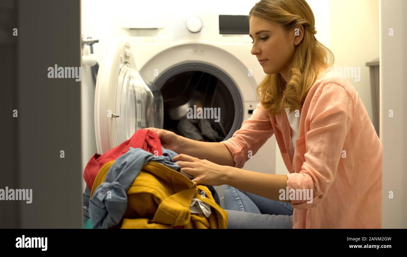 Woman putting clothes in washing machine, home laundry service, daily ...