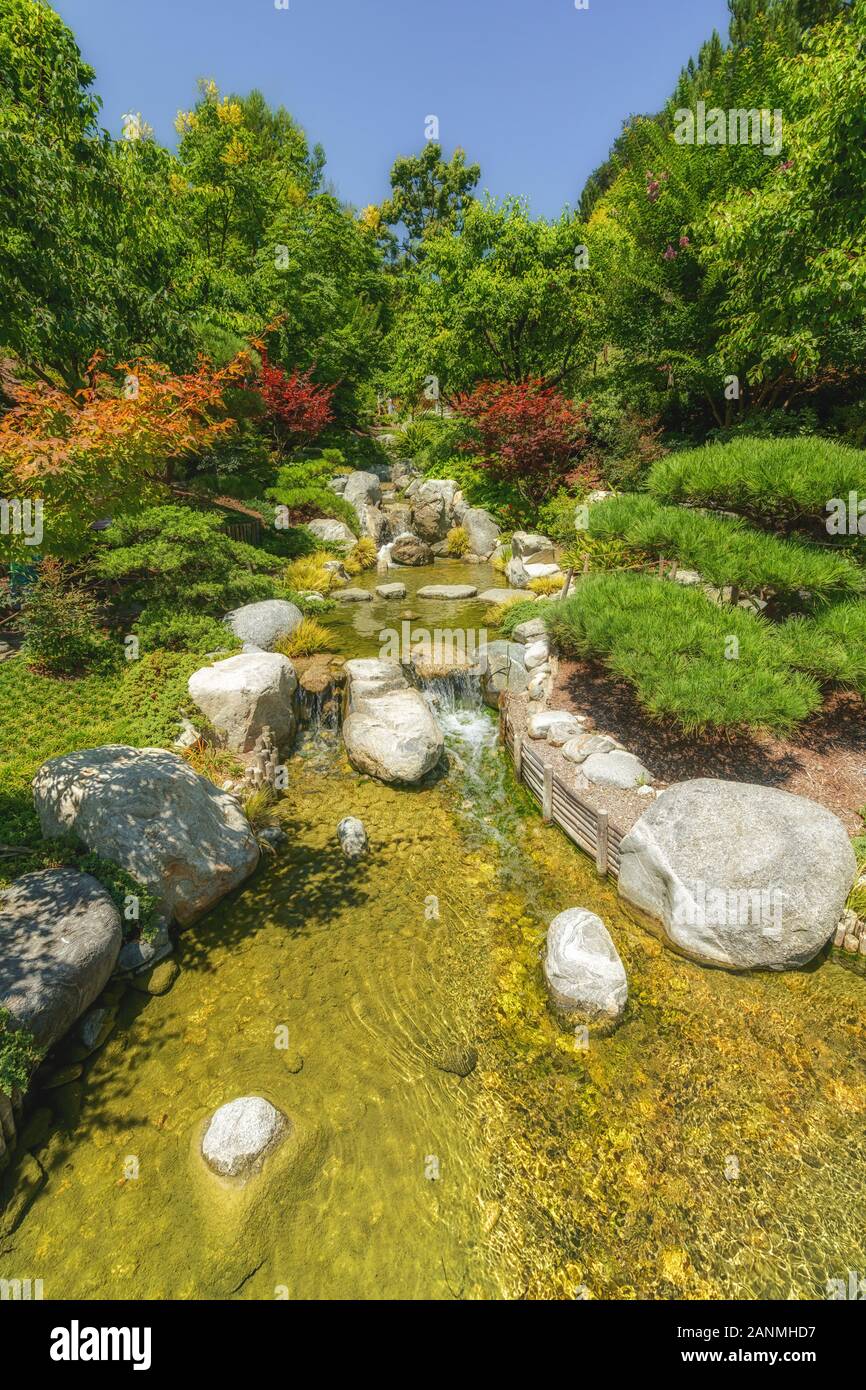 Japanese garden waterfall. Water flows around stones in flowing river ...