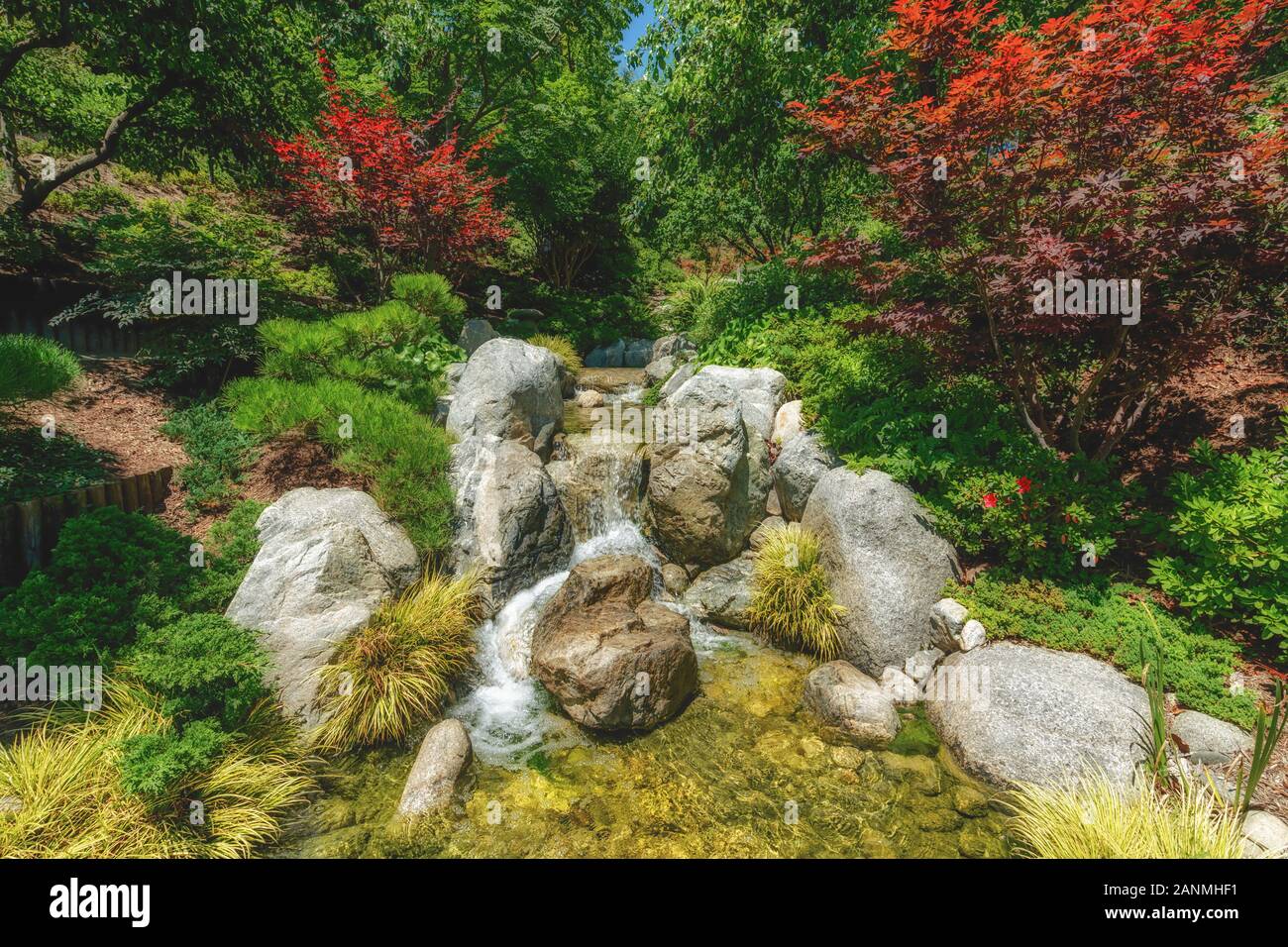 Japanese garden waterfall. Water flows around stones in flowing river ...