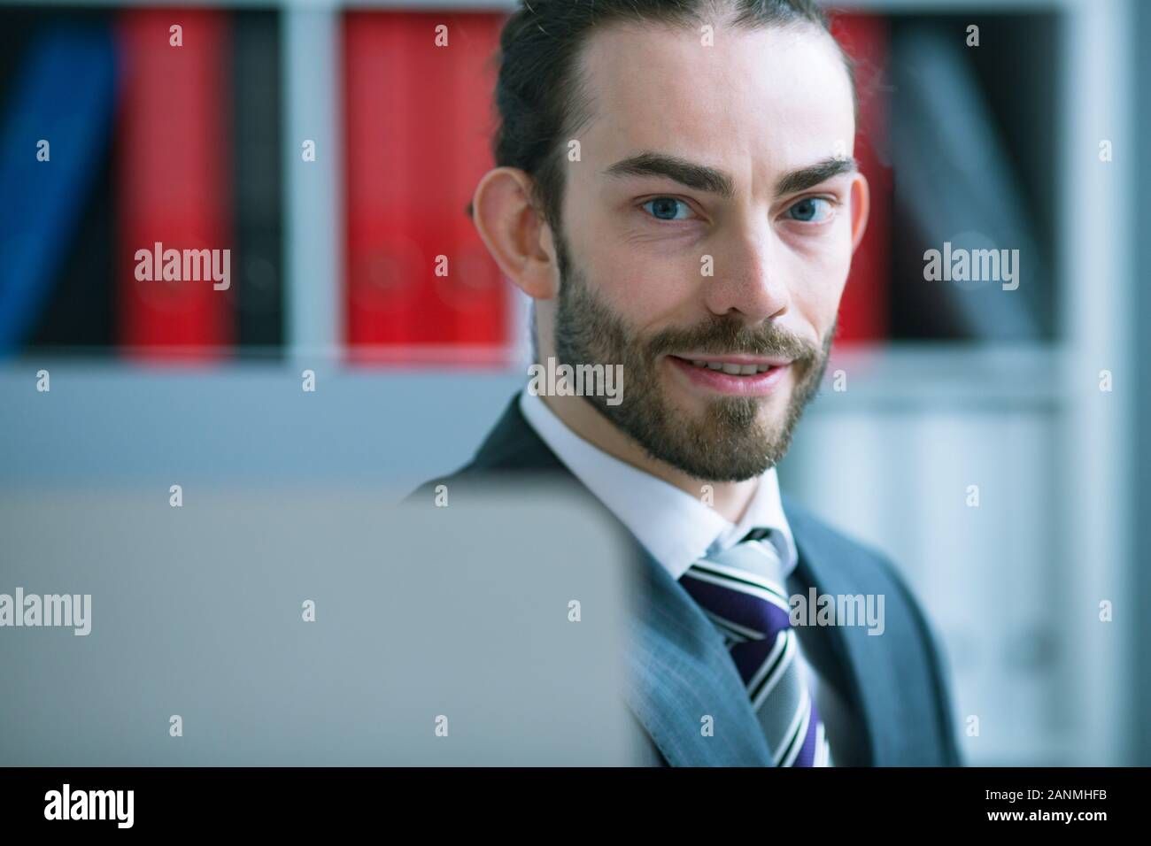 Businessman peeping from behind the monitor, looking into the camera ...