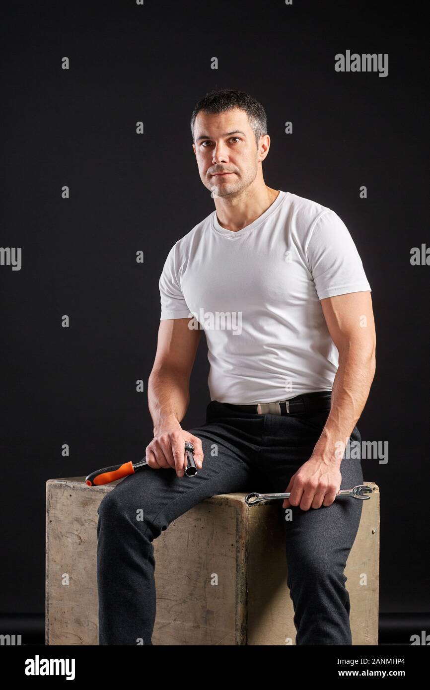 Athletic man with wrench on a black background. Not a typical worker ...