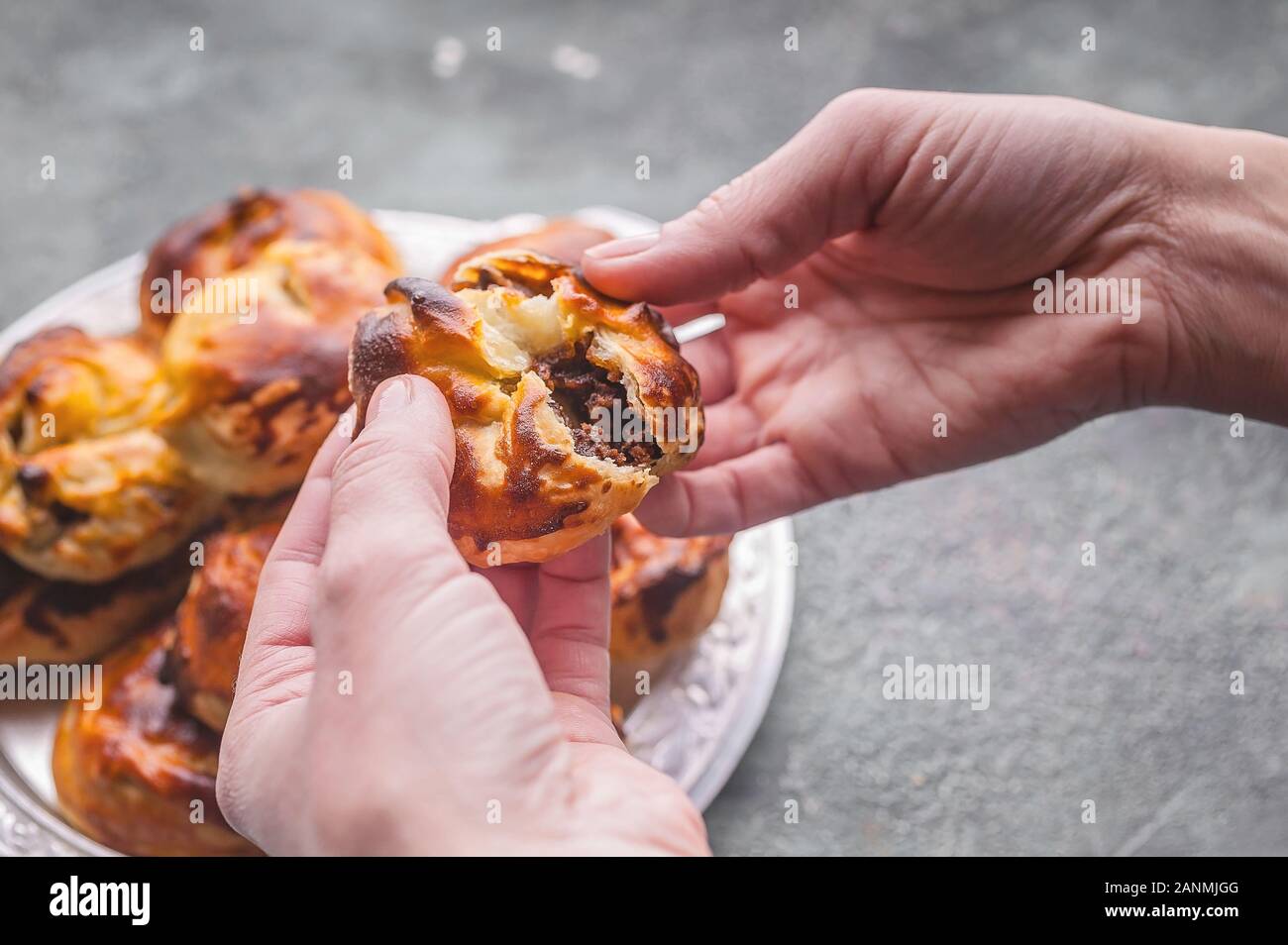 Female hands hold sweet homemade chocolate-nut buns on a silver platter ...