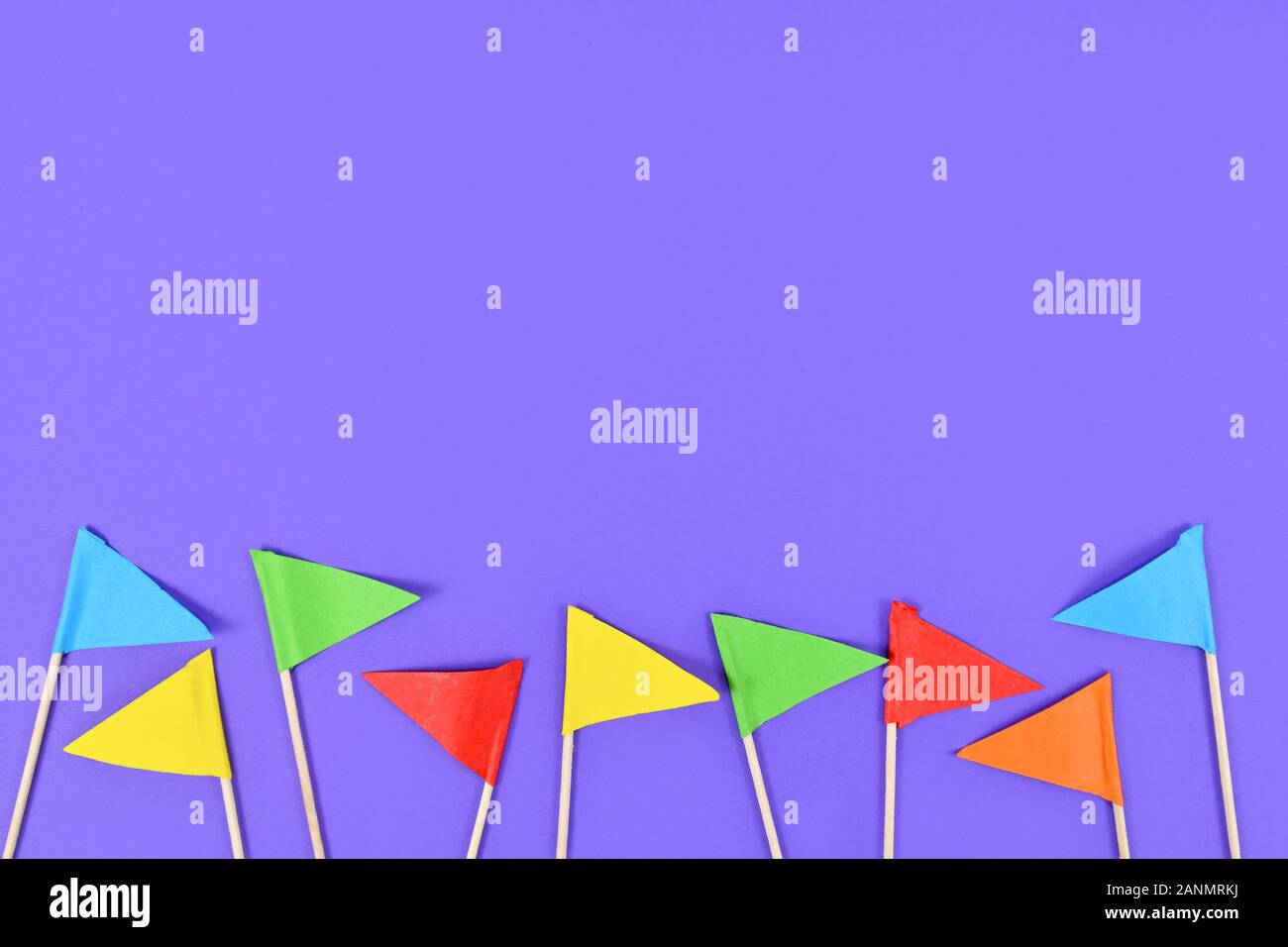 Colorful small paper flags at bottom on purple background with copy ...