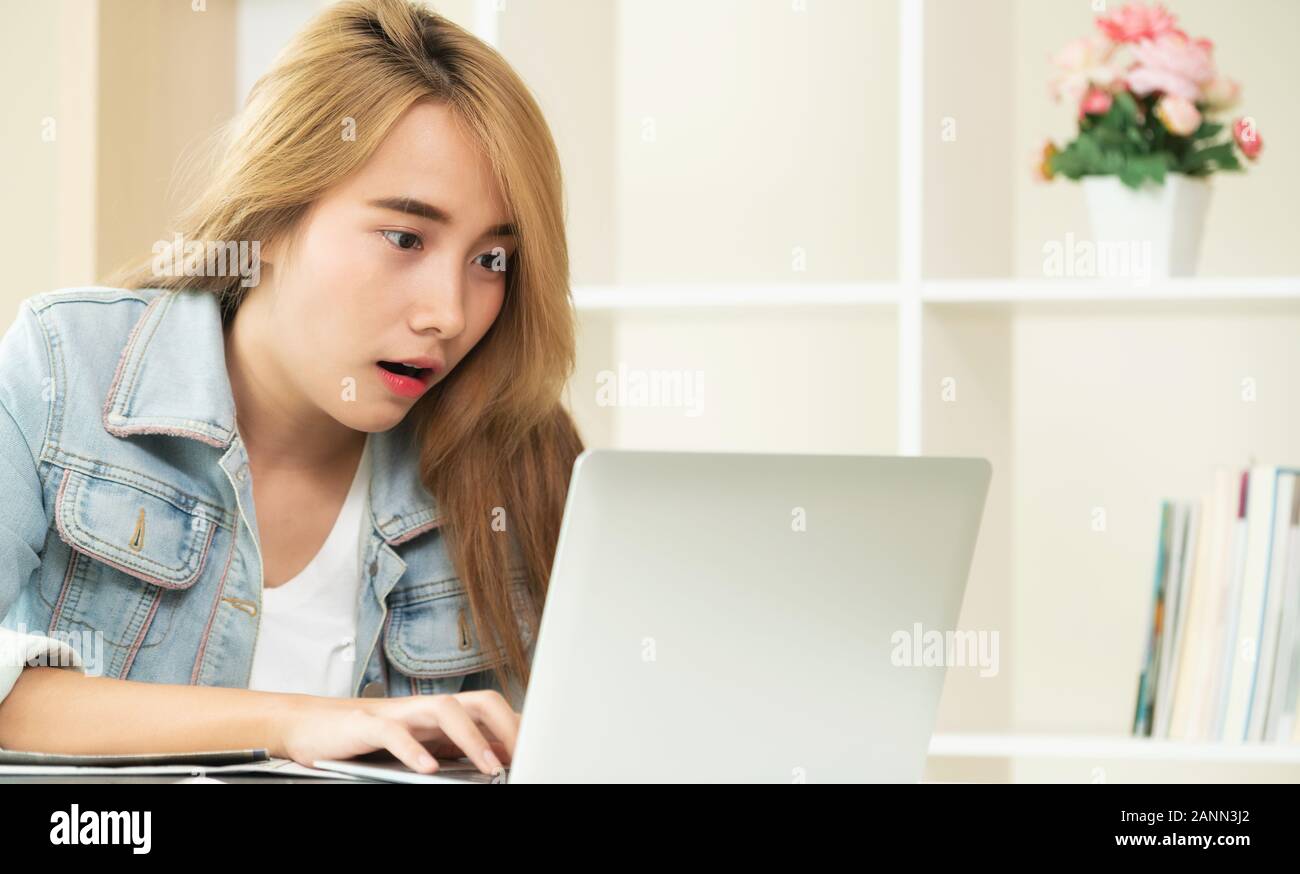 Cute woman feels amazed, excited or surprised while looking at laptop ...
