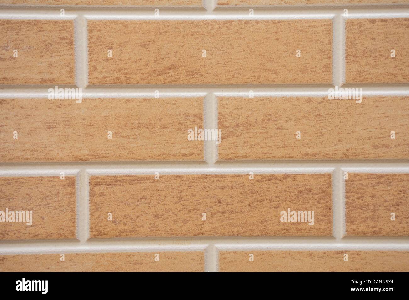 Beige textured brick interior or exterior wall with white grout. A ...