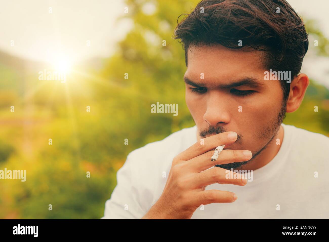 Young Man Smoking Cigarette In The Outdoors And Nature Background Stock