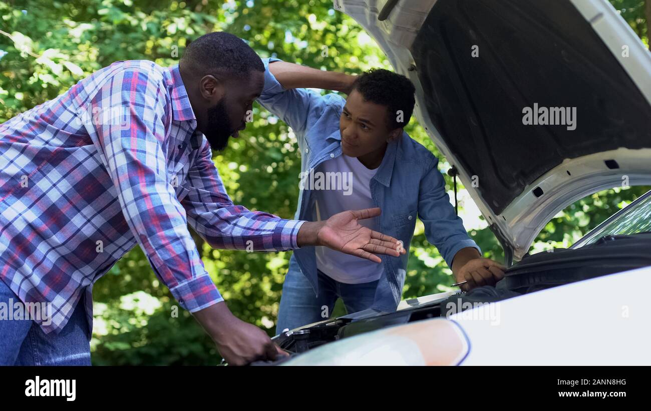 Son hitting upside head while father scolding, repairing car together ...