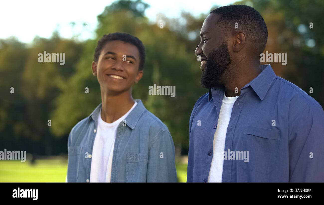 Happy parent and male child standing outdoors smiling each other ...
