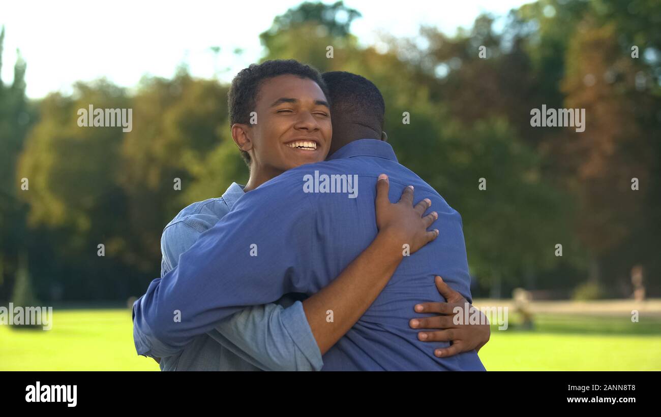 Male teenager hugging elder brother outdoors, family meeting happiness ...