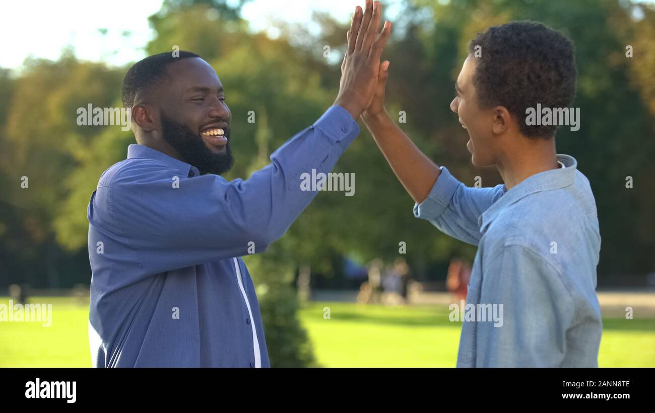 Cheerful black brothers giving high five outdoors, happy family, close ...