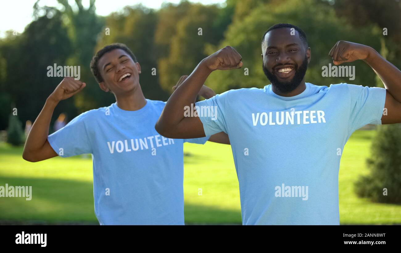 Young male volunteers showing arm muscles, strength gesture, teamwork ...