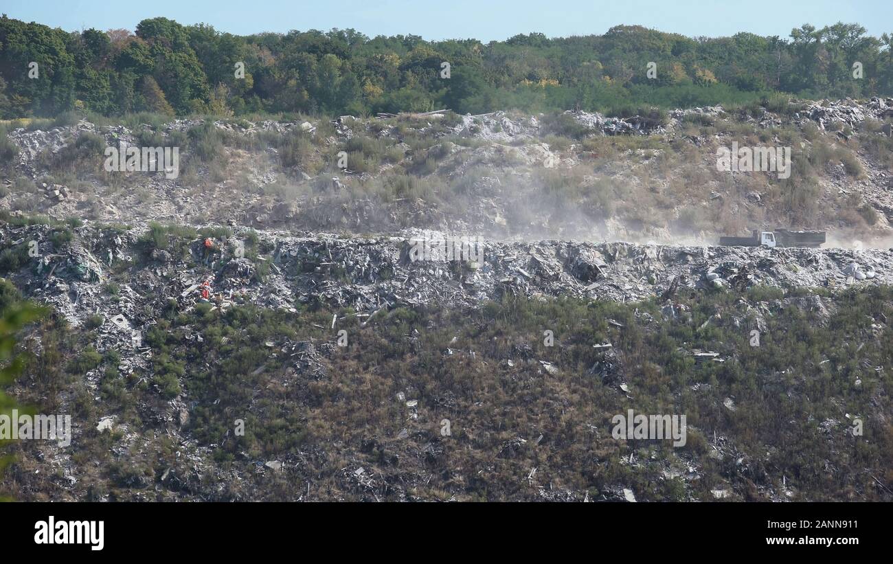 Trucks riding among garbage in abandoned place, nature pollution, smog ...