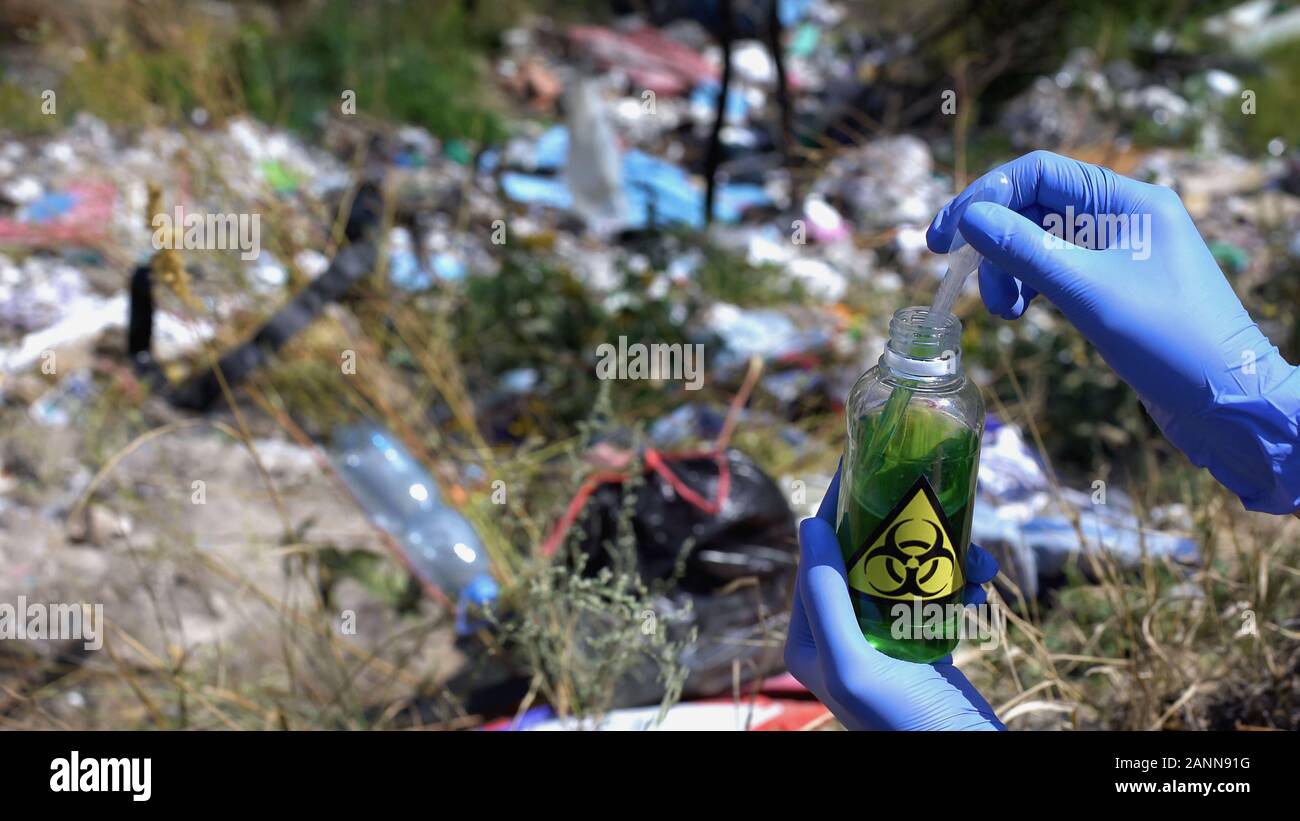 Hand in glove taking sample from bottle with biohazard sign against ...