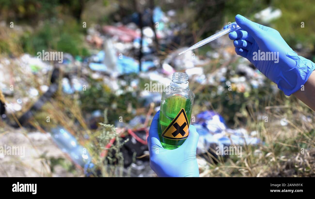 Ecologist in gloves taking sample from bottle with cross sign in ...