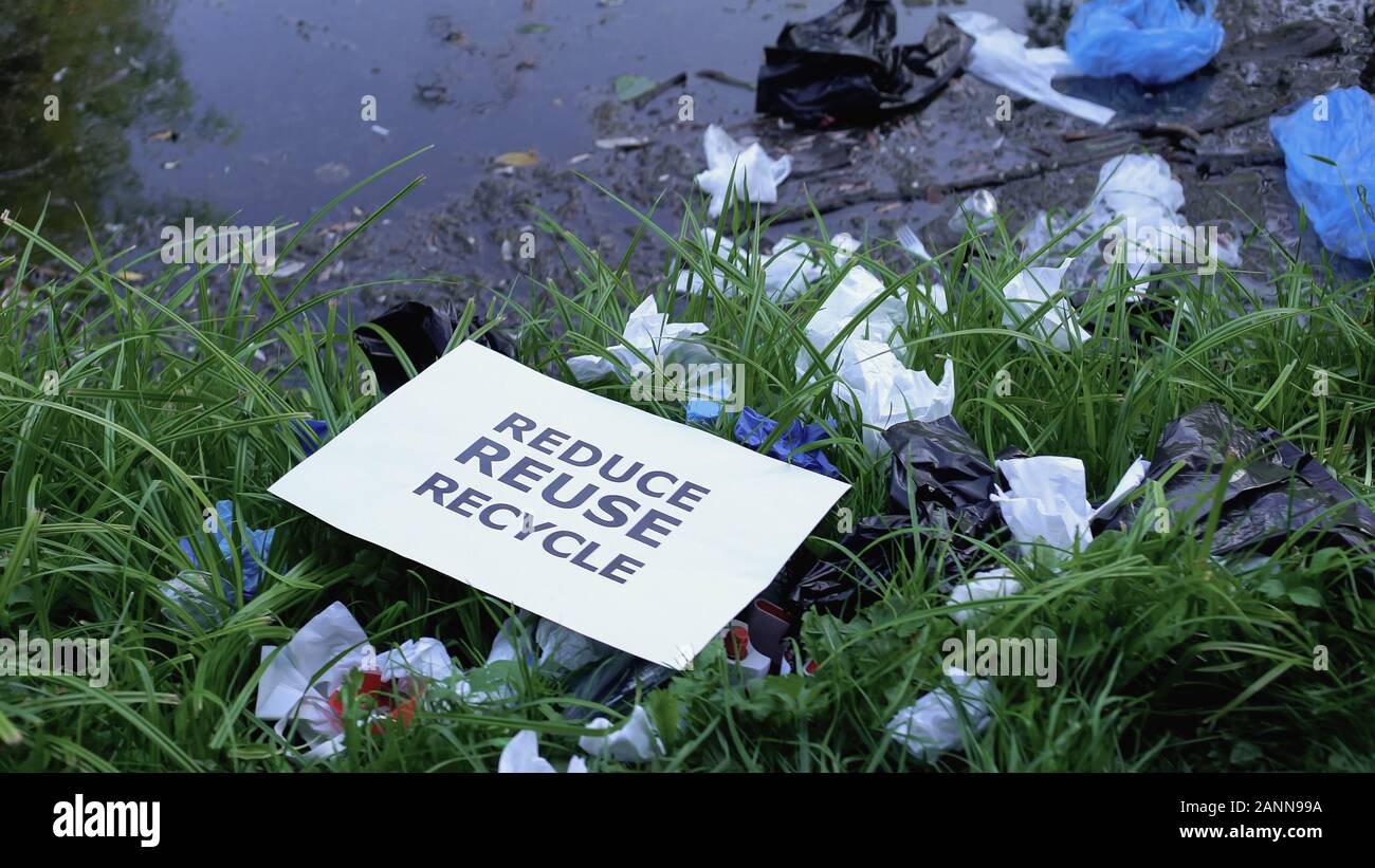 Cardboard with reduce reuse recycling phrase lying on polluted grass ...