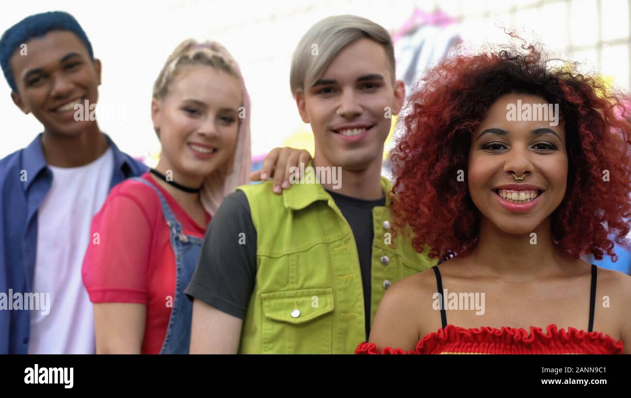 Positive modern millennials smiling camera graffiti building background ...