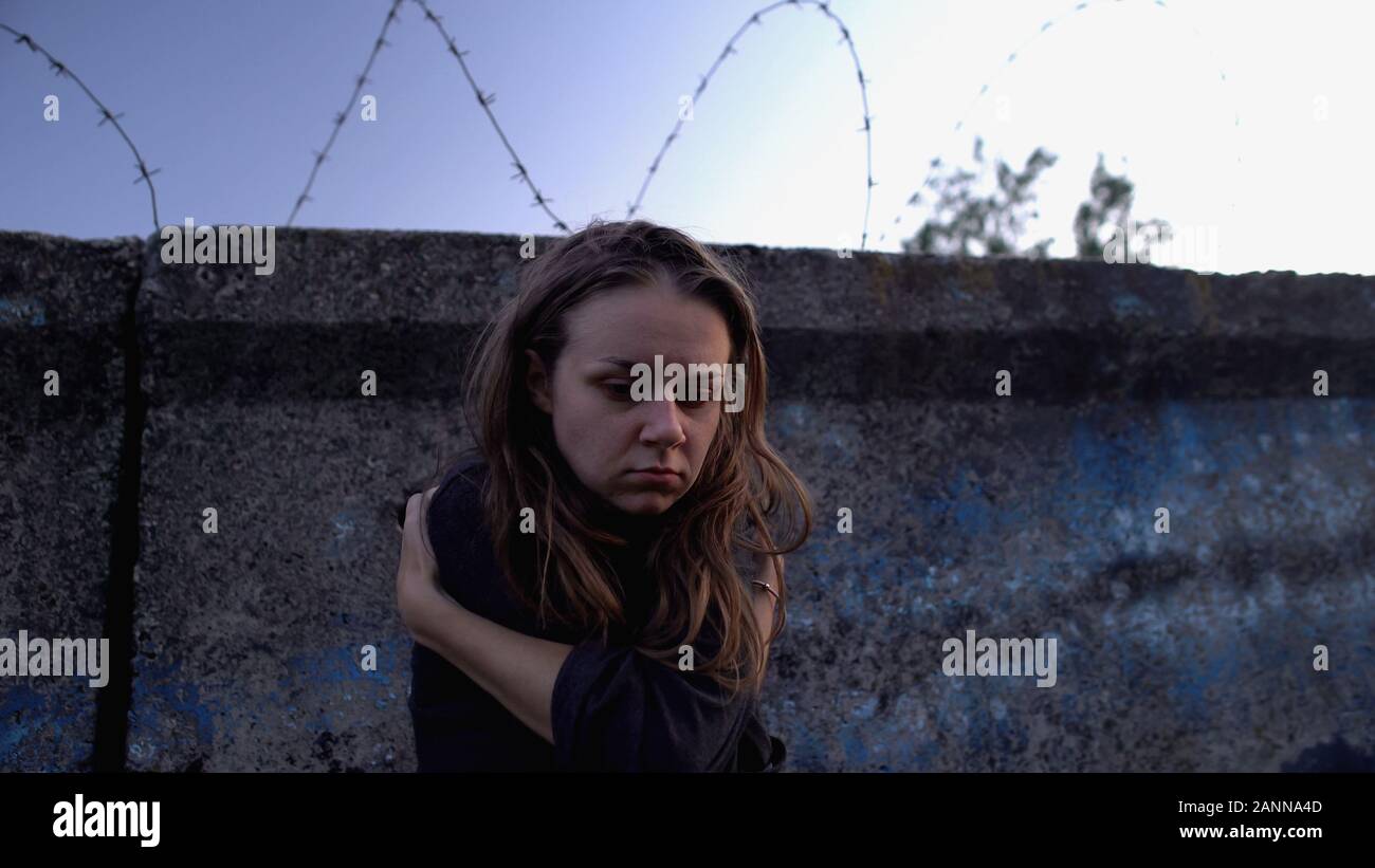Scared refugee standing near wall with barbed wire, war witness ...