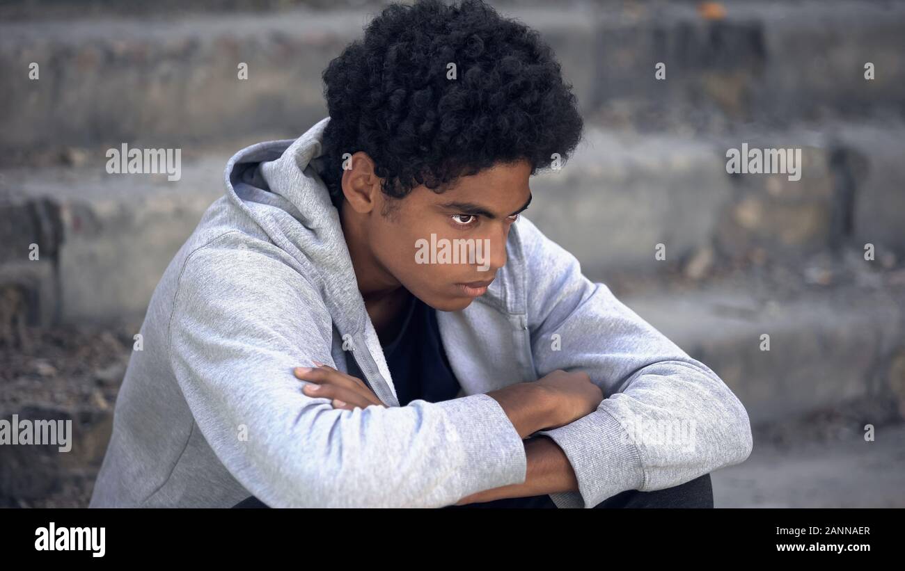 Unhappy male teenager sitting city stairs alone, running from home ...