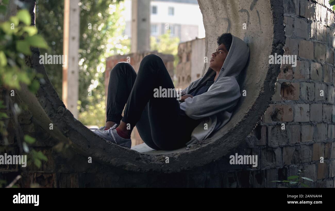 Sad lonely student in hoodie sitting alone abandoned building, puberty ...