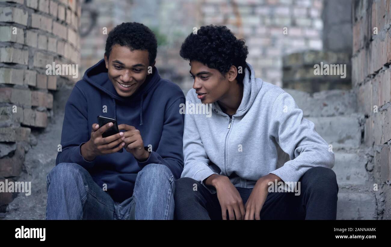 African teenagers watching smartphone photos having fun together ...