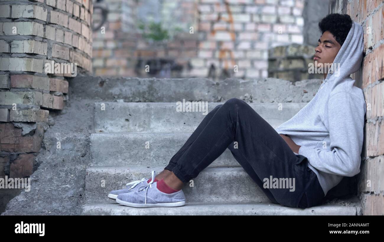 Homeless tired male child sitting abandoned building stairs, running ...