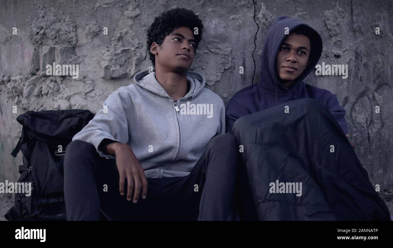 Black male teen supporting homeless friend sitting street, poverty ...