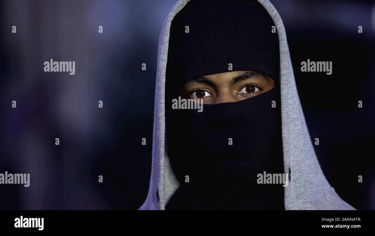 African bandit in balaclava mask preparing to commit crime at night ...