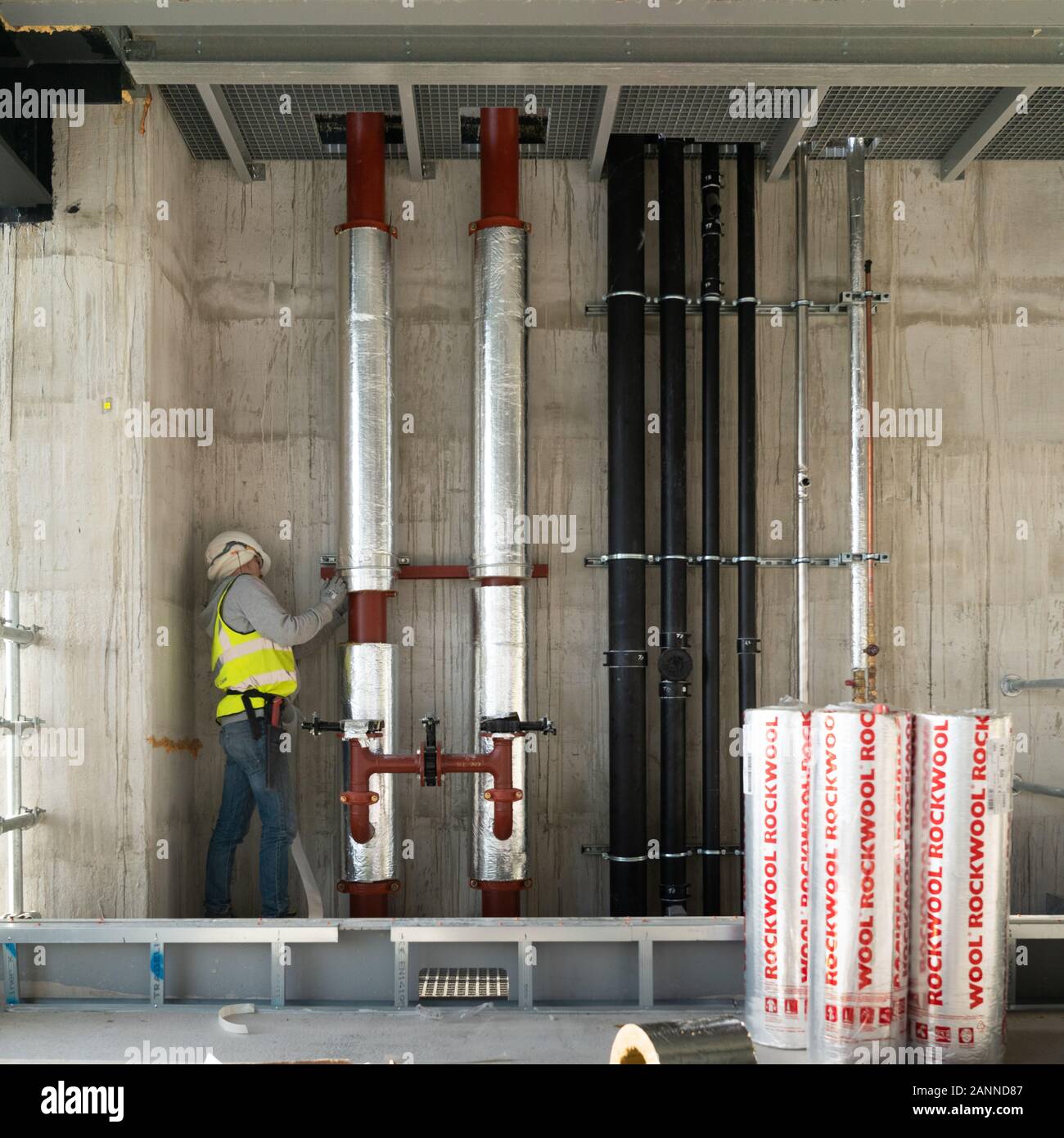 Construction worker applying insulation to pipe work Stock Photo - Alamy