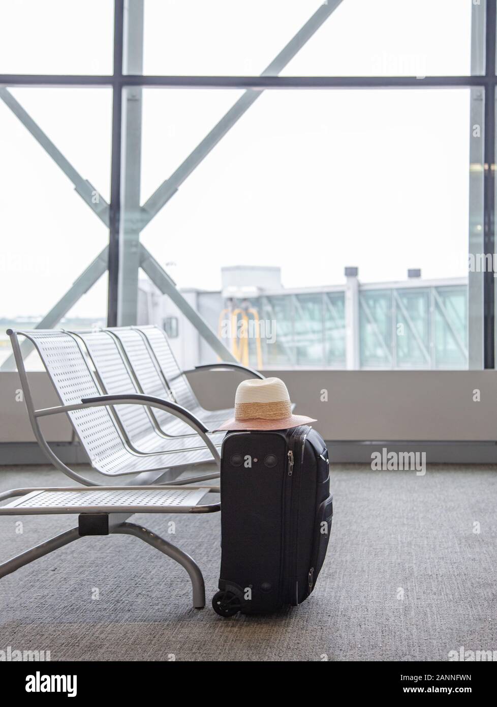 Suitcase in an airport waiting area, concept of lost luggage, one black ...
