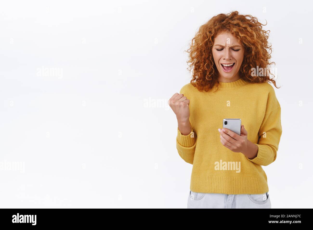 Satisfied, happy triumphing redhead curly woman, fist pump and saying ...