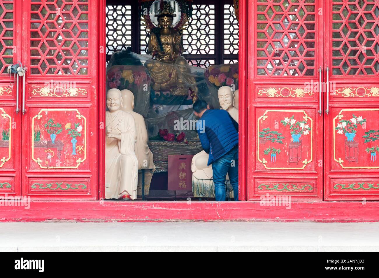 A chinese man painting buddha statues within Jile Temple in Harbin ...