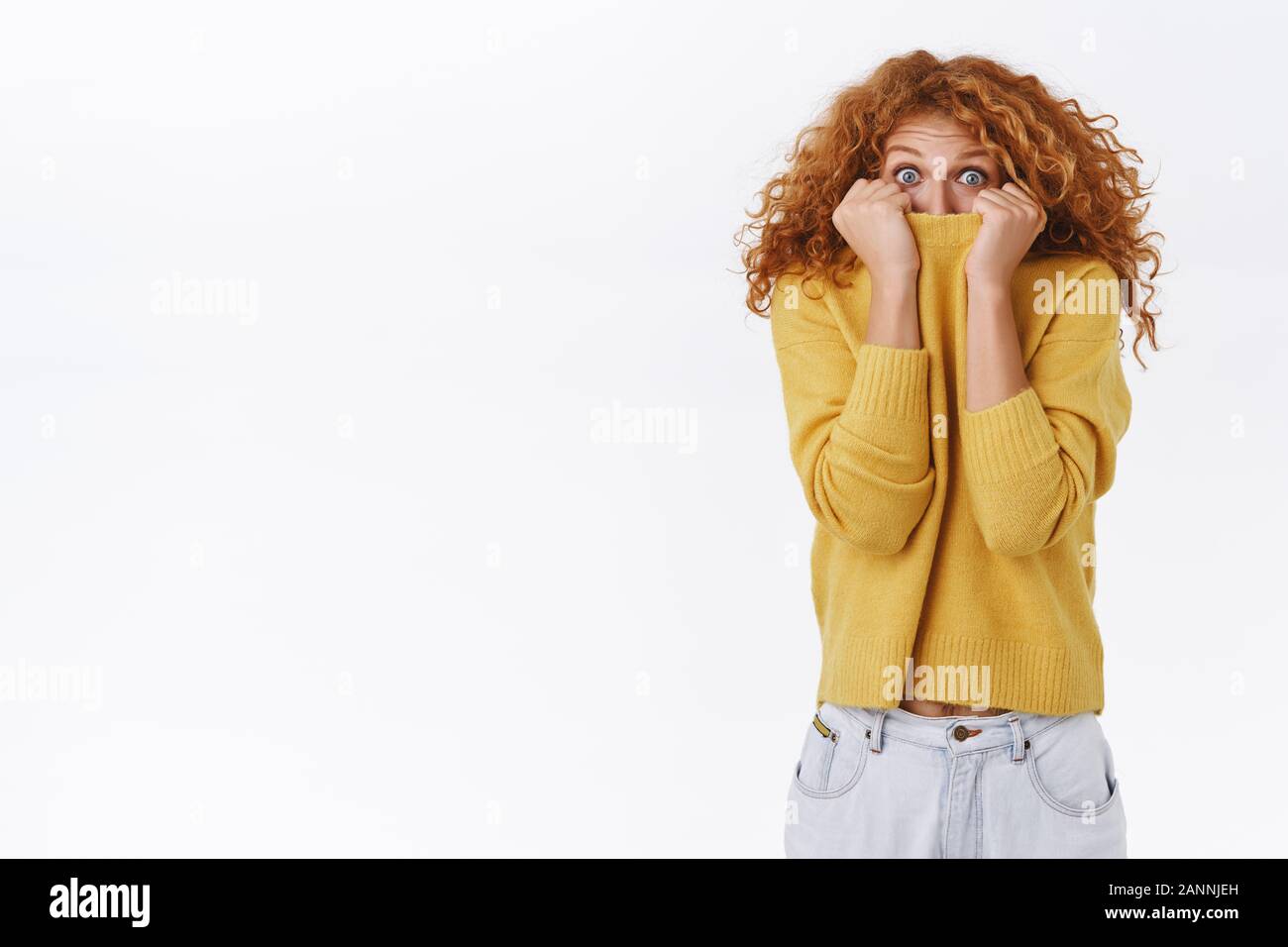 Scared, silly cute timid girl, hiding her face in sweater collar, pull ...