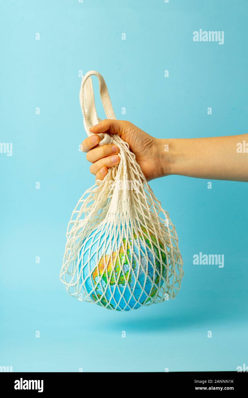 Zero waste concept. String bag in a female hand with earth globe ...