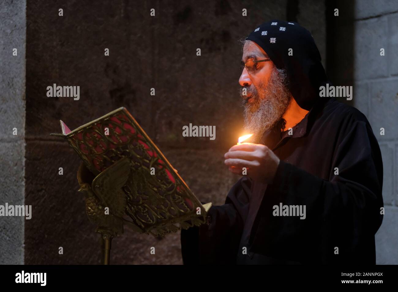 Coptic Orthodox priest holds a candle as he prays inside the Church of ...