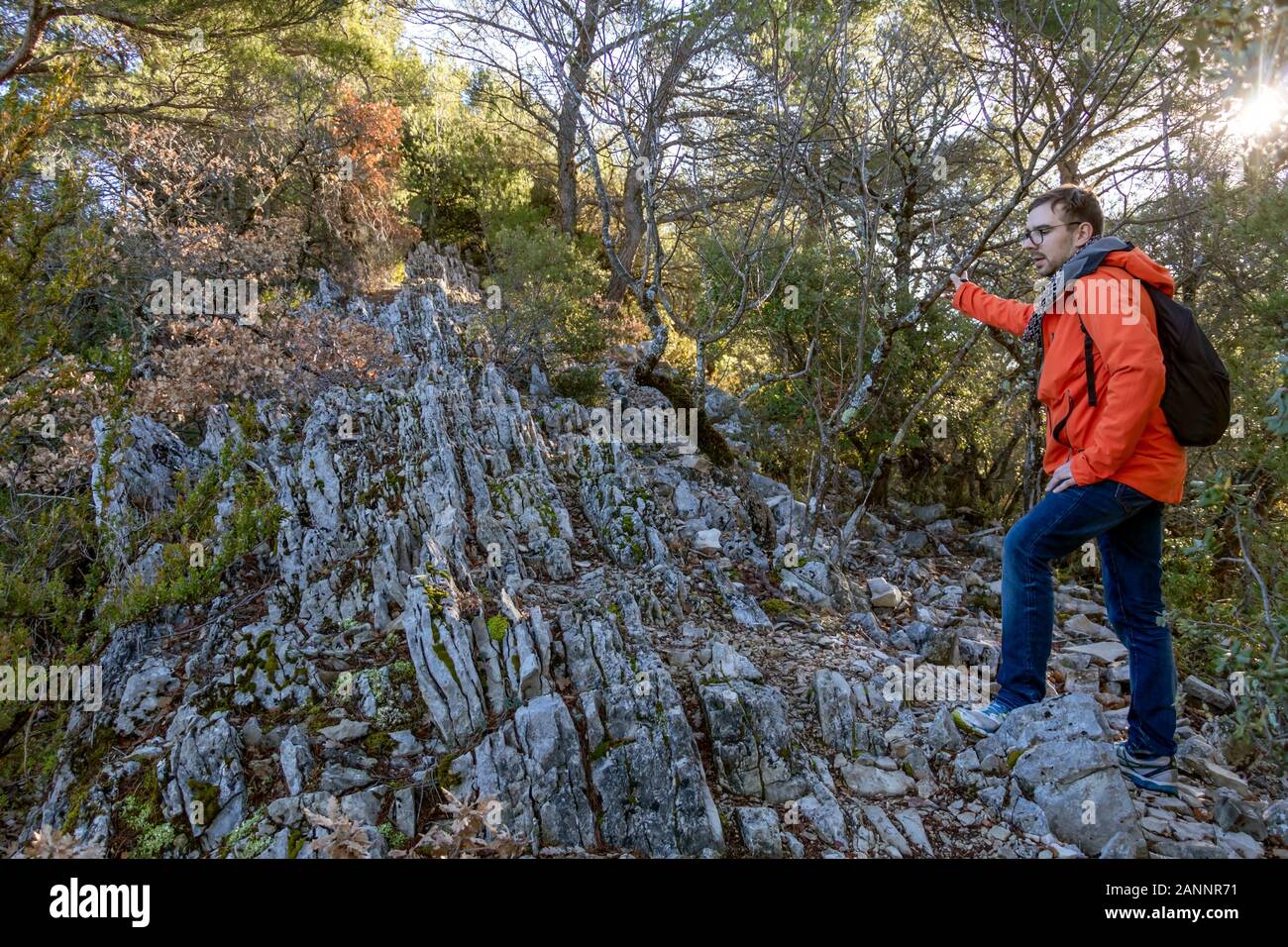 Young casual man climbing gray rock cliffs surrounded by mountains in ...