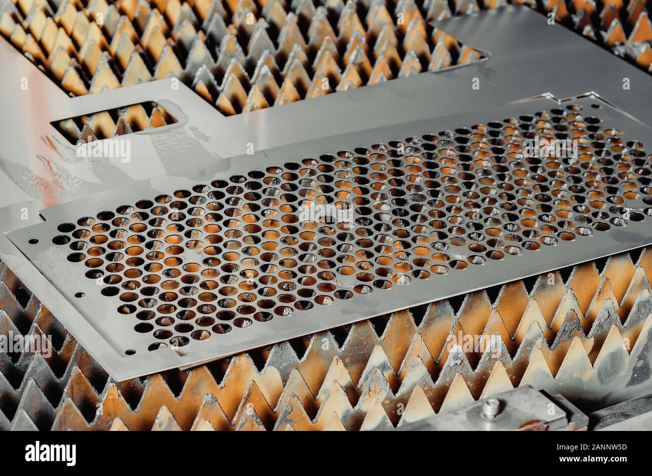 Metal plate with laser-cut circles on a metal base of a laser machine ...