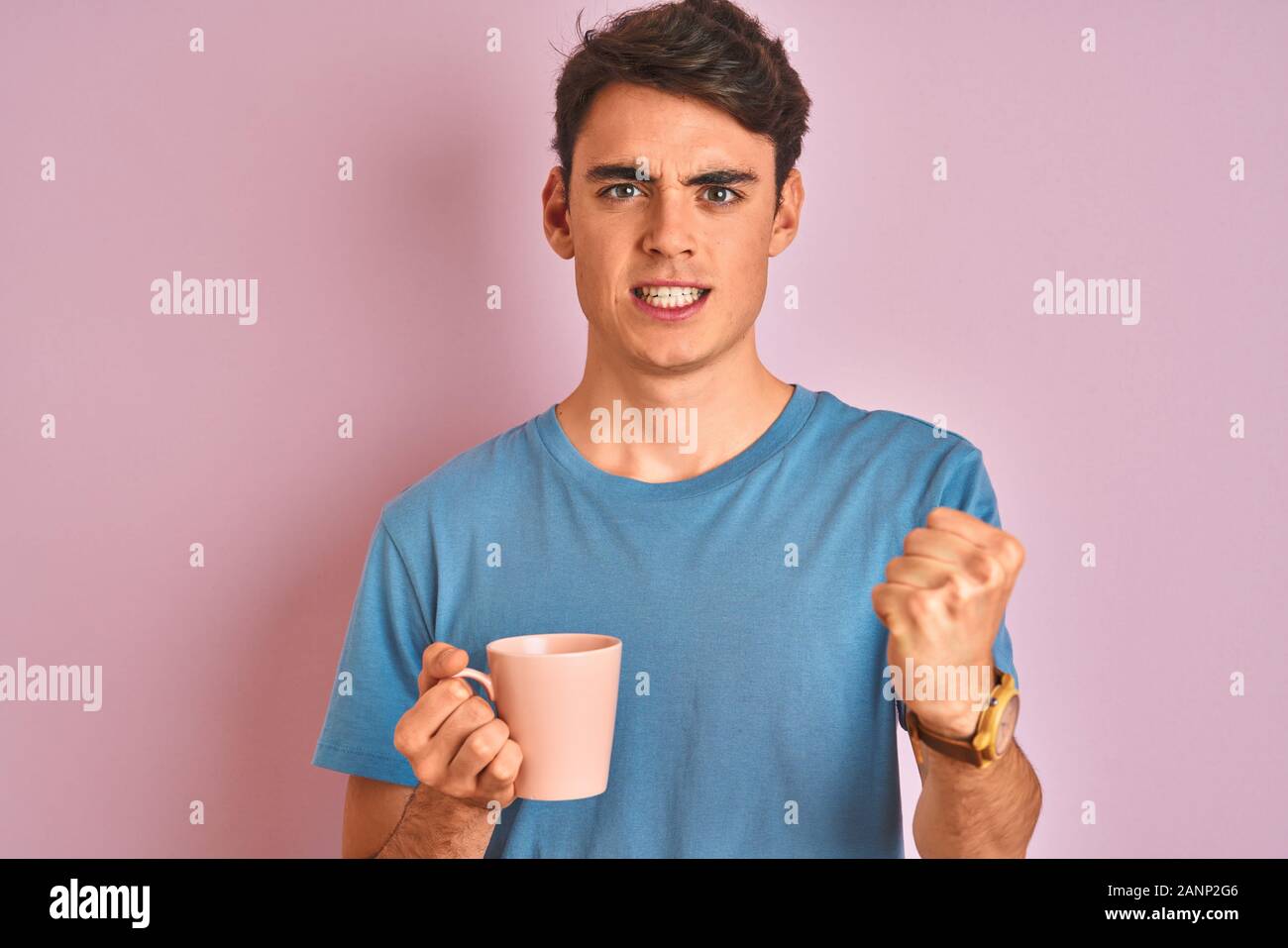 Teenager boy drinking a cup of coffee over isolated pink background ...