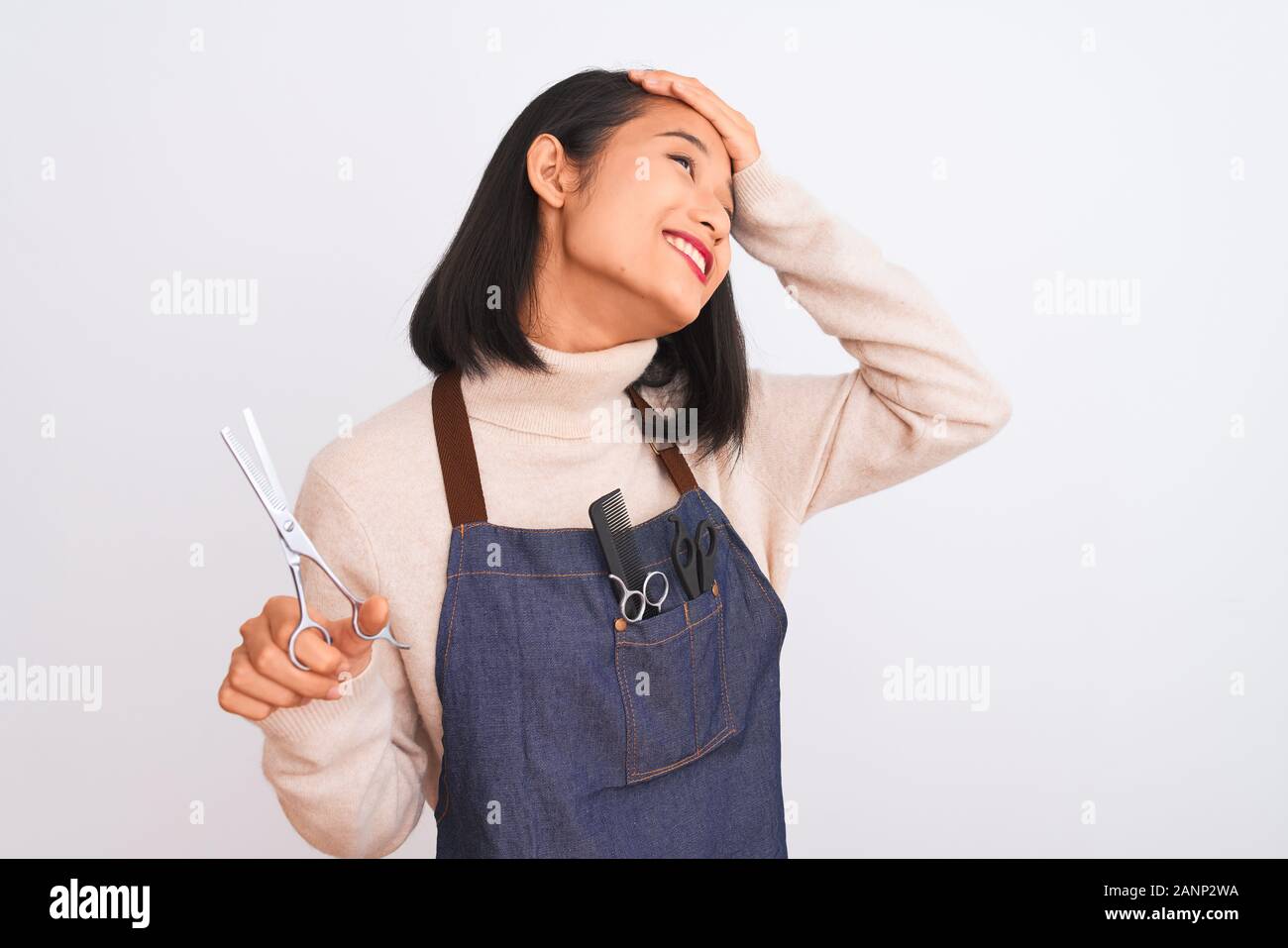 Chinese hairdresser woman wearing apron holding scissors over isolated ...