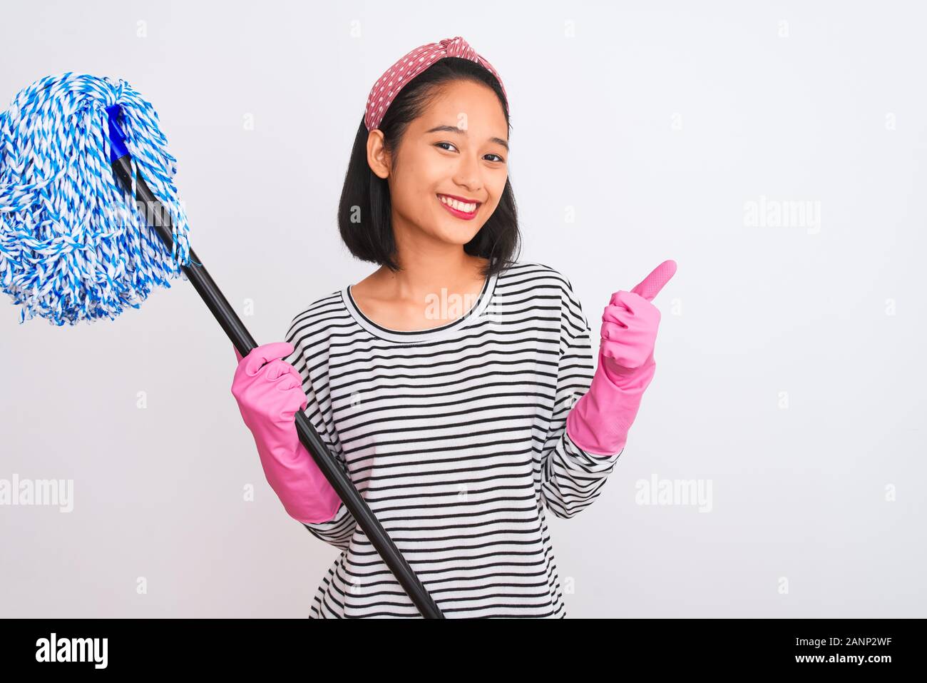 Young chinese cleaner woman wearing gloves holding mop over isolated ...