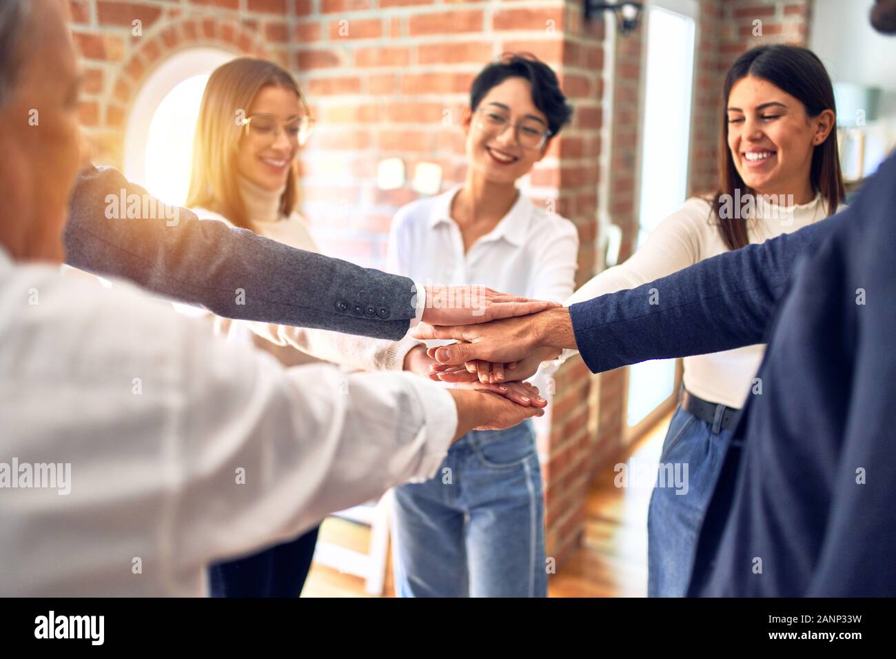 Group of business workers standing with hands together at the office ...