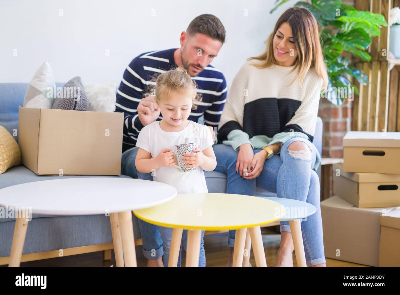 Beautiful family, parents sitting on the sofa drinking coffee looking ...