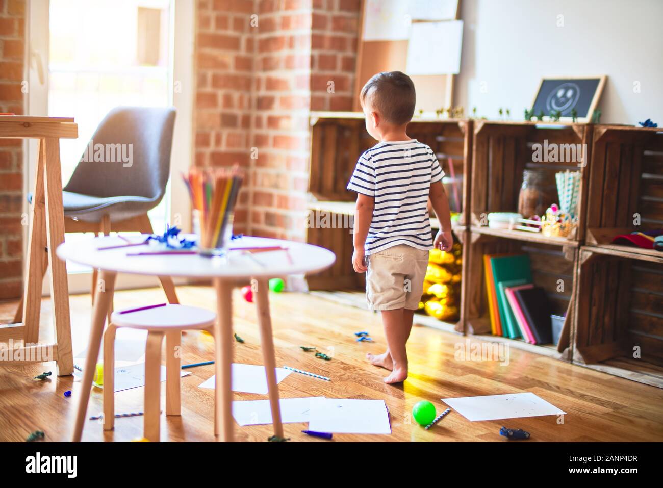 Beautiful toddler boy standing at kindergarten with lots of toys Stock ...