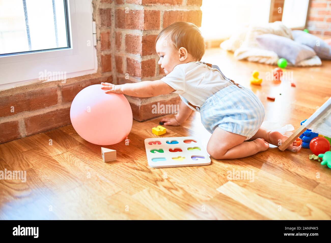 Adorable toddler crawling around lots of toys at kindergarten Stock ...