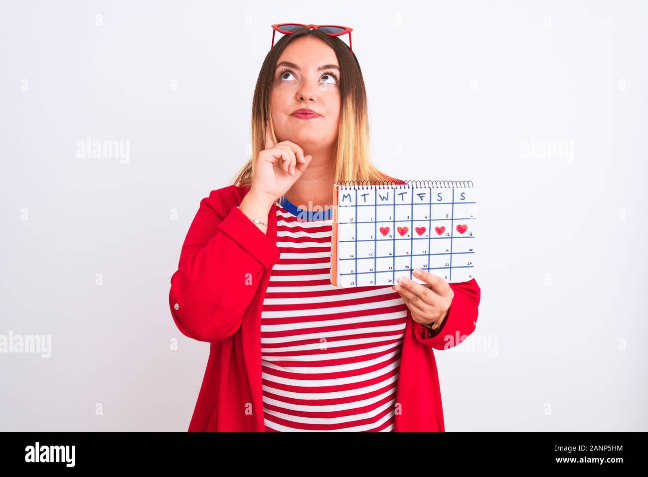 Young beautiful woman holding period calendar standing over isolated ...