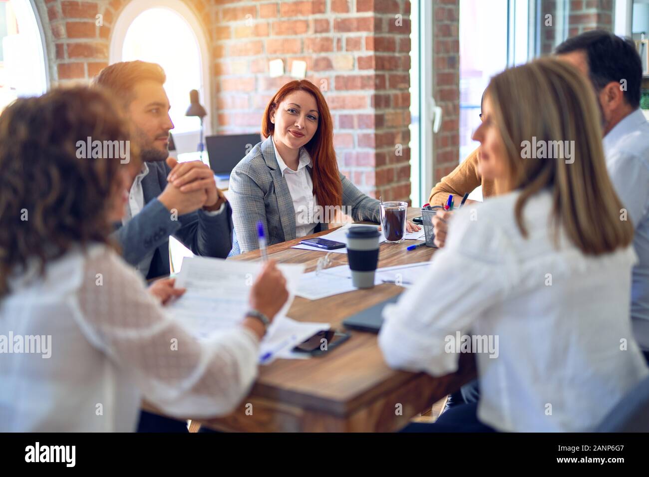 Group of business workers working together. Sitting on desk speaking at ...