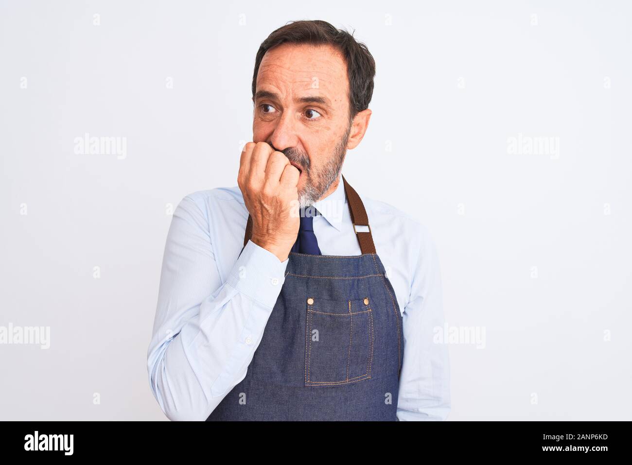 Middle age shopkeeper man wearing apron standing over isolated white ...